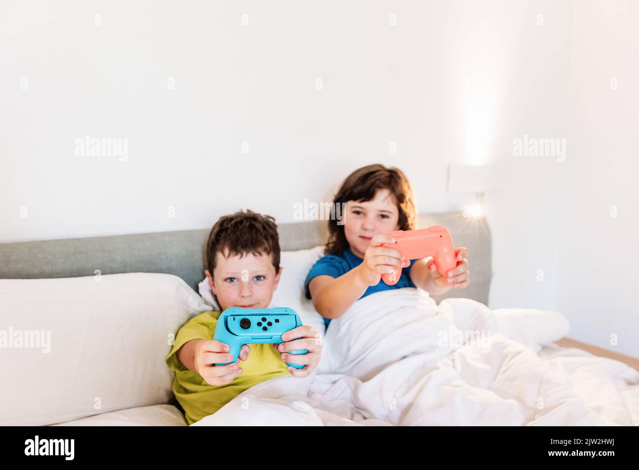 Focused siblings with gamepads playing interesting video game while ...
