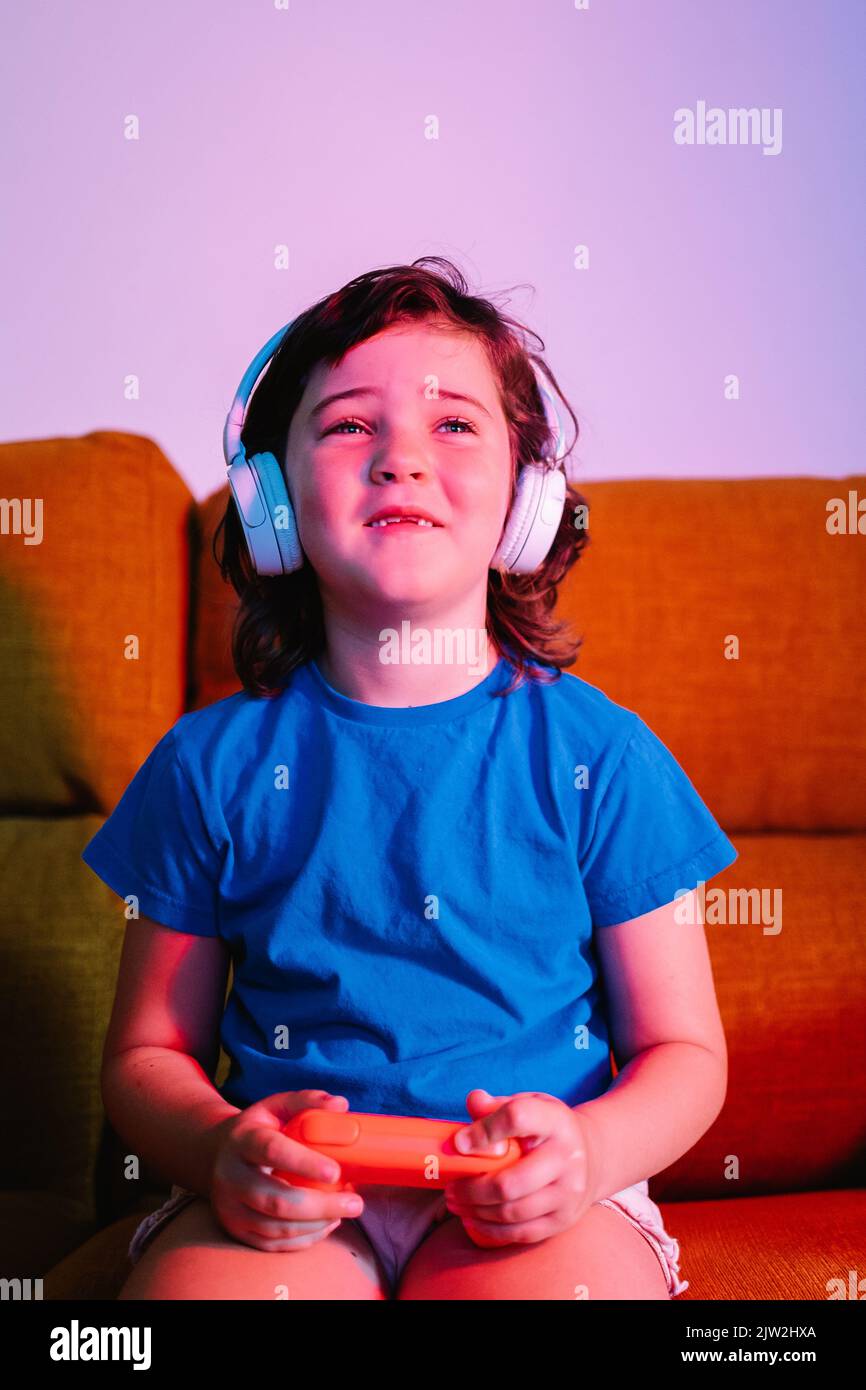 Upset girl in headphones playing interesting video game with gamepad ...