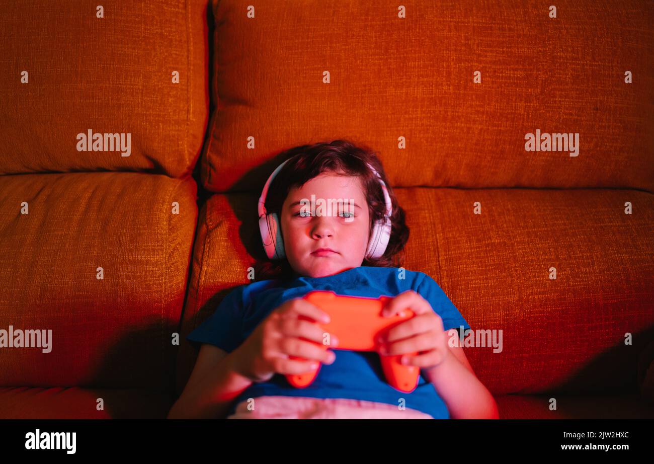 Upset girl in headphones playing interesting video game with gamepad ...