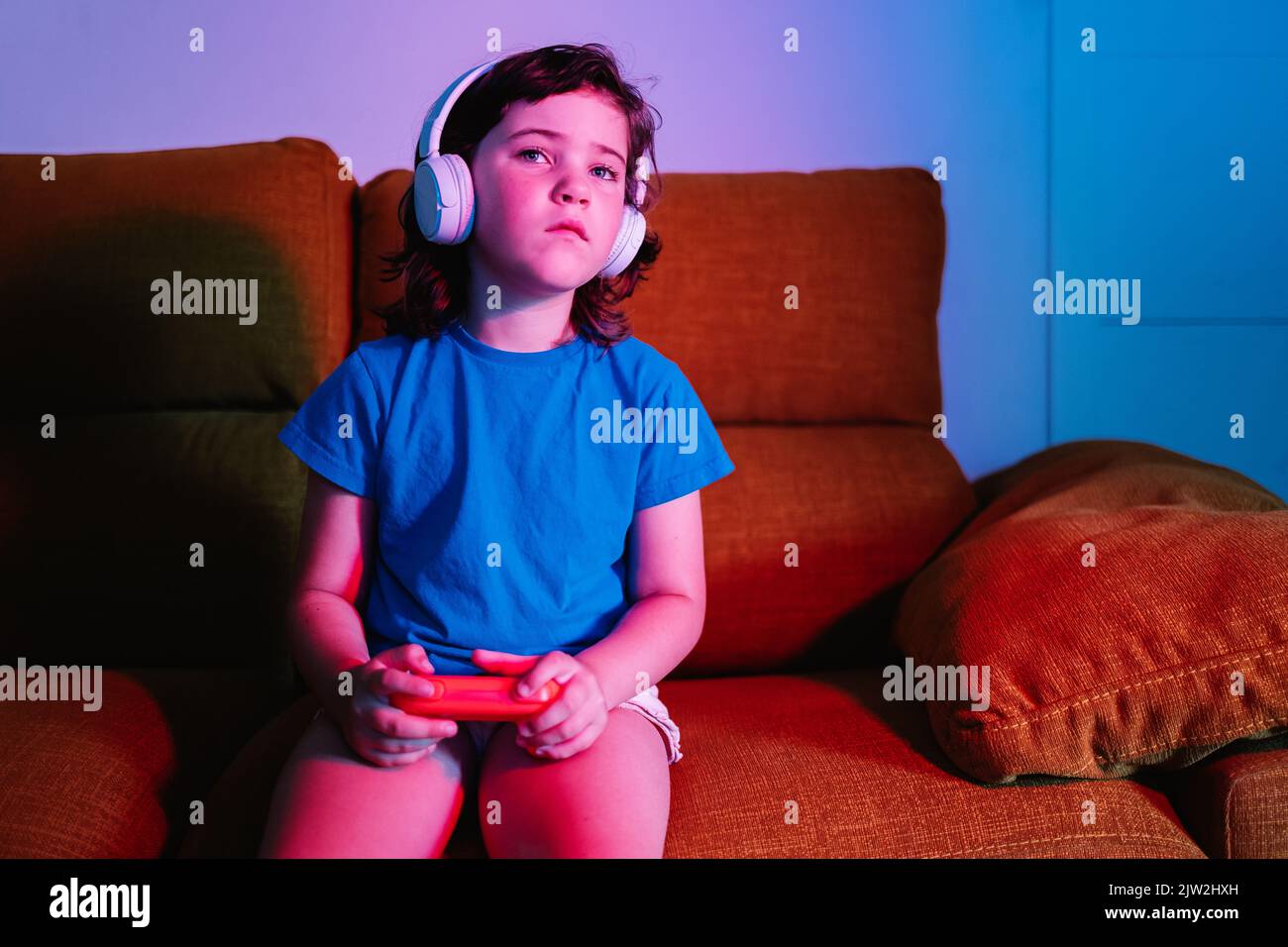 Upset girl in headphones playing interesting video game with gamepad ...