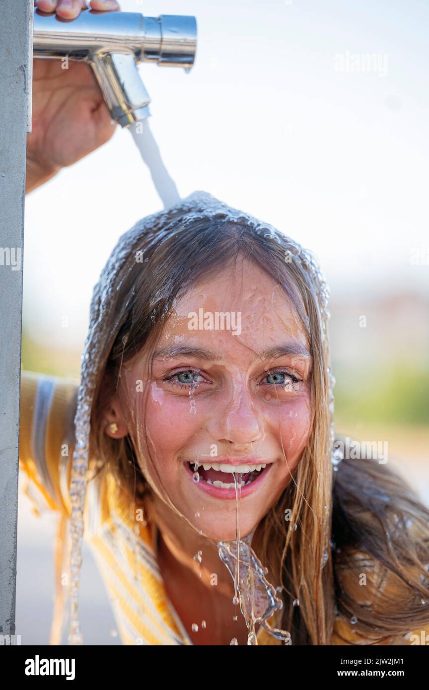 Joyful Teenage Girl Looking At Camera With Smile While Standing Under Water Stream On Embankment