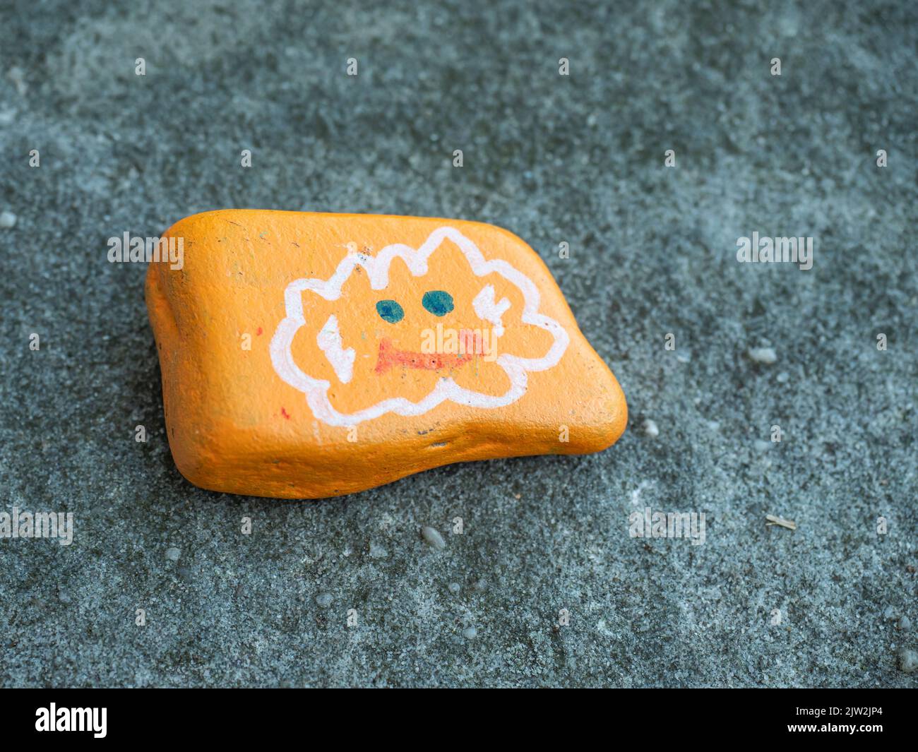 Laughing face painted on a small stone. Children game of painted ...