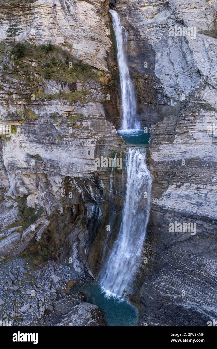 Clean water falling from rough rocky cliff and forming rapid stream in ...