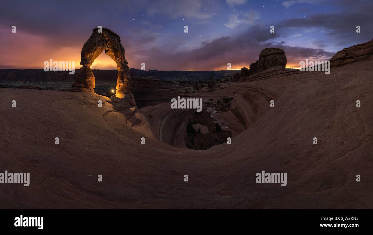 Unrecognizable traveler standing with flashlight near natural stone ...