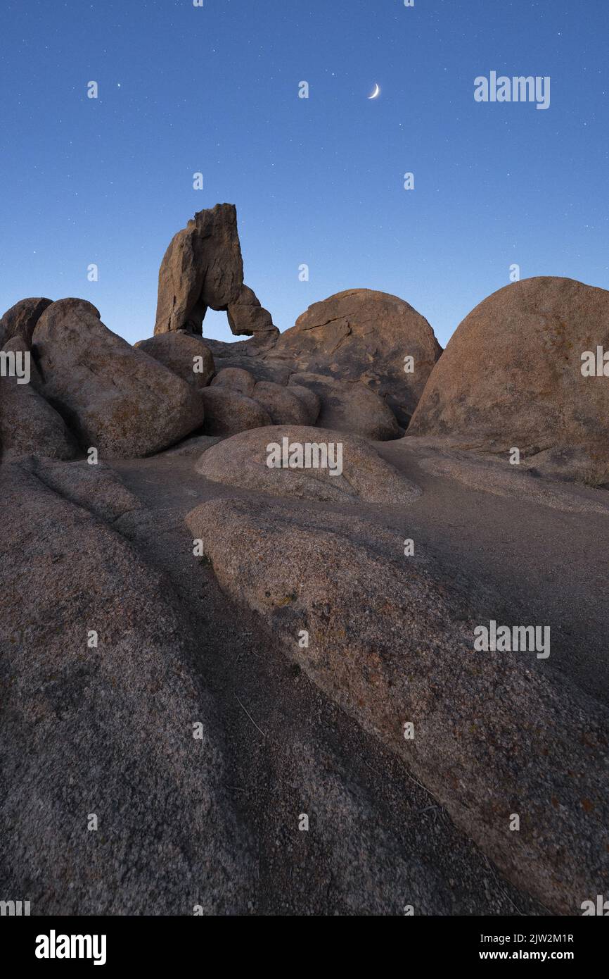 Low angle of smooth boulders and rock arch located against night sky in ...
