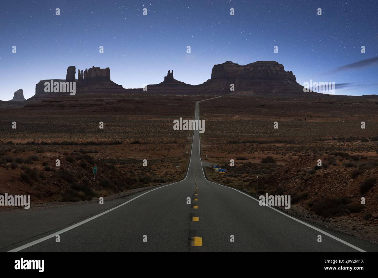 Straight asphalt road going towards uneven rock formations against ...