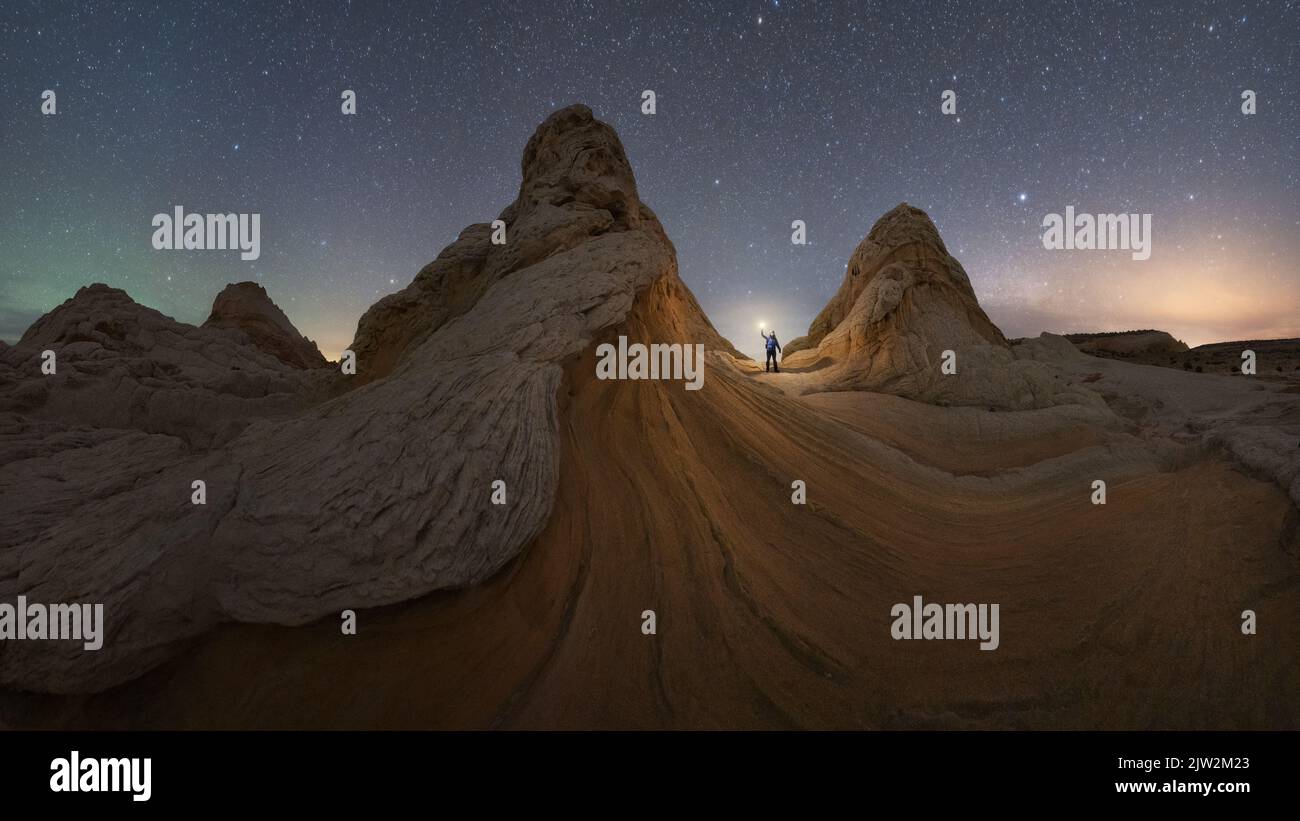 Tourist with bright flashlight standing on rocky surface near mountain ...