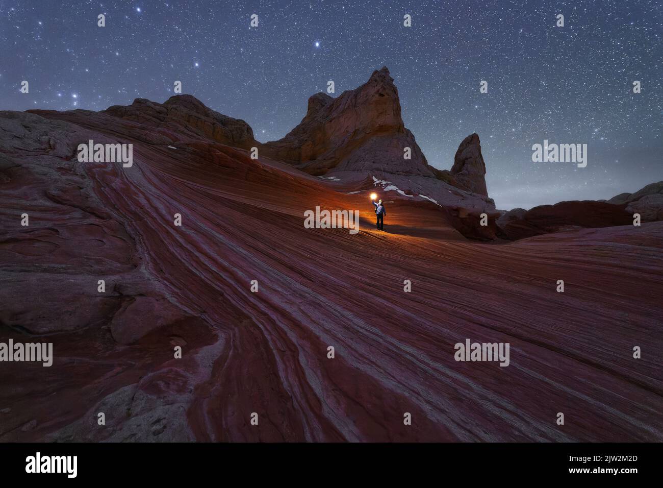 Tourist with bright flashlight standing on rocky surface near mountain ...