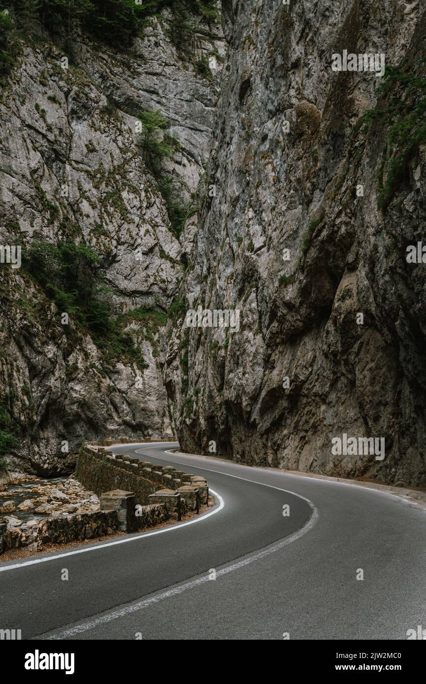 Breathtaking scenery of narrow curvy asphalt road amidst massive rocky ...