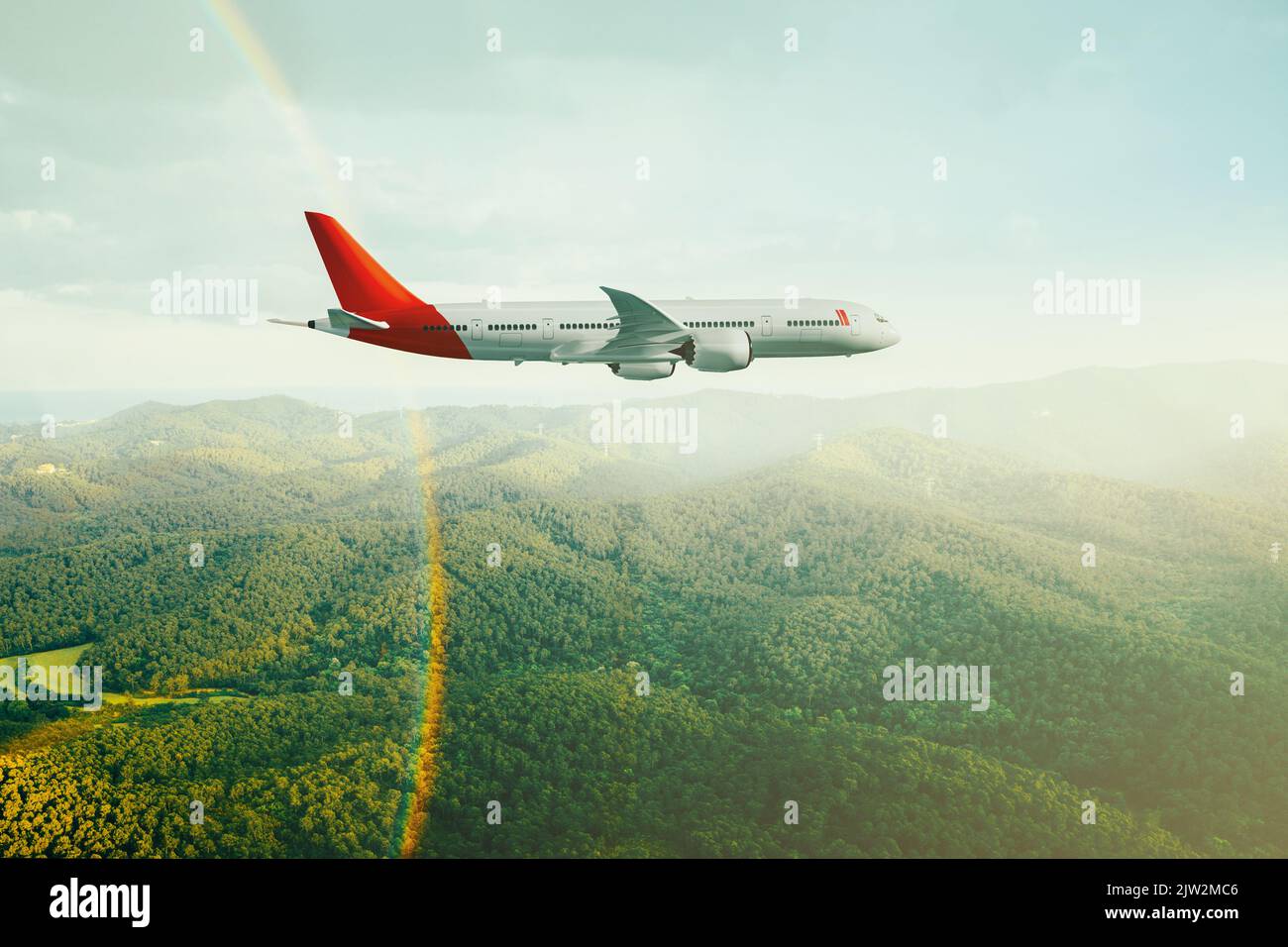 Side view of a commercial airplane flying over green mountains at ...