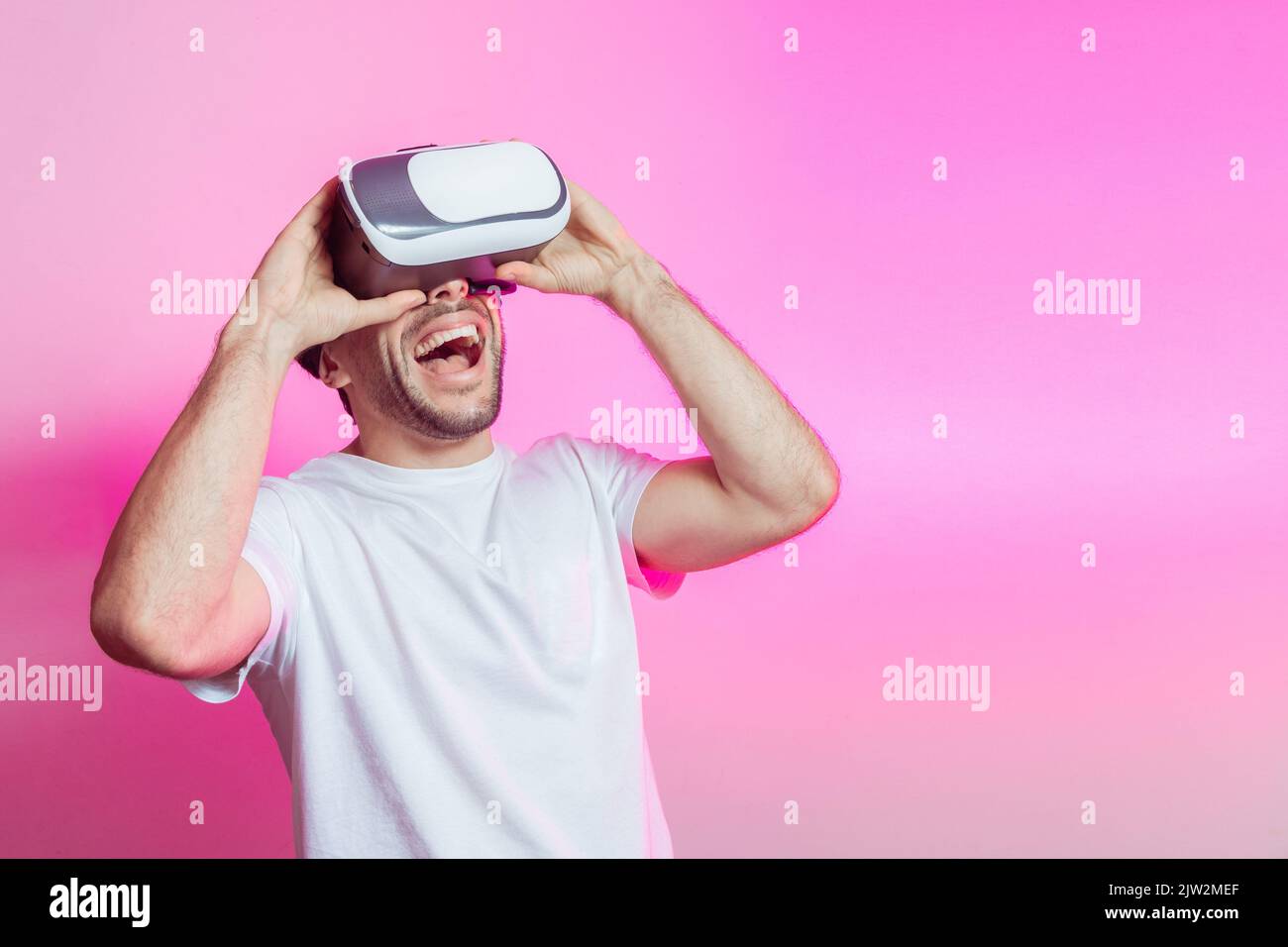 Positive male gamer in modern VR headset celebrating victory while ...