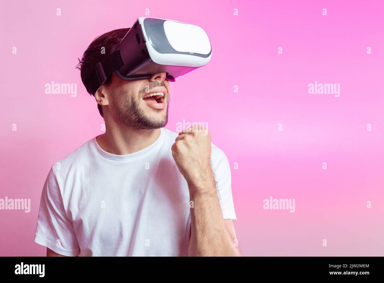Positive male gamer in modern VR headset celebrating victory with ...