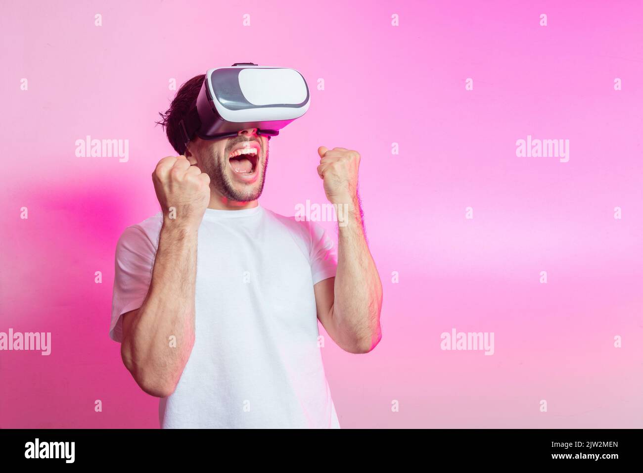 Positive male gamer in modern VR headset celebrating victory with ...