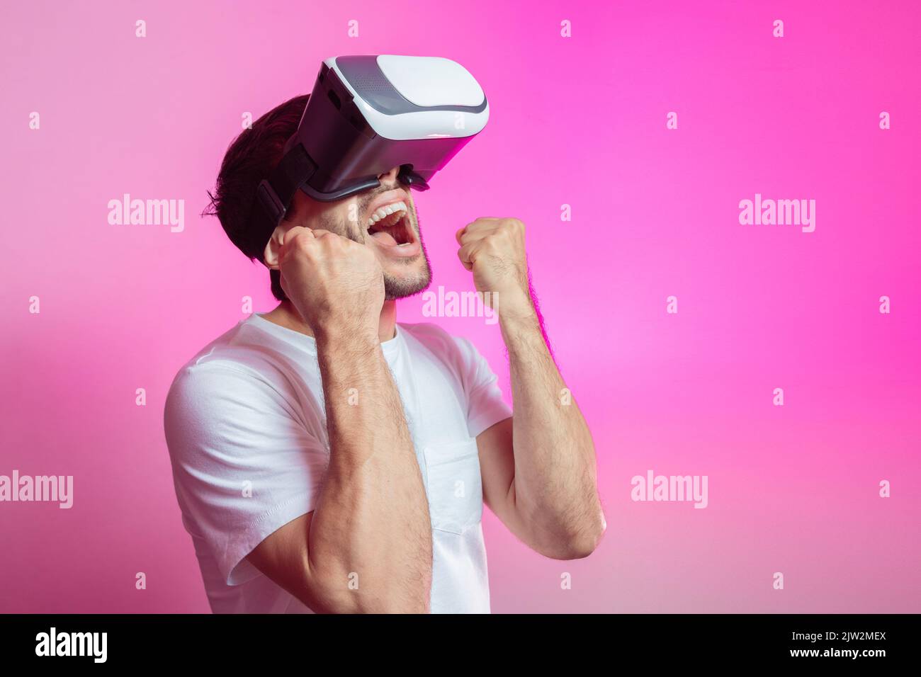 Positive male gamer in modern VR headset celebrating victory with ...