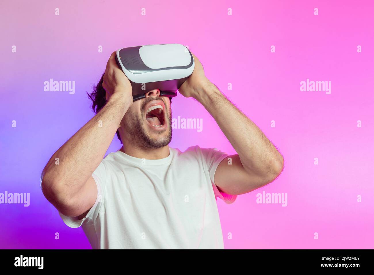 Positive male gamer in modern VR headset celebrating victory while ...