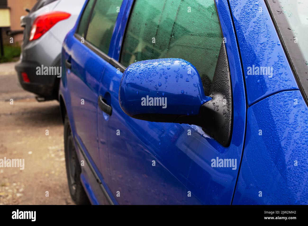 Wet side mirror of blue car close up Stock Photo - Alamy
