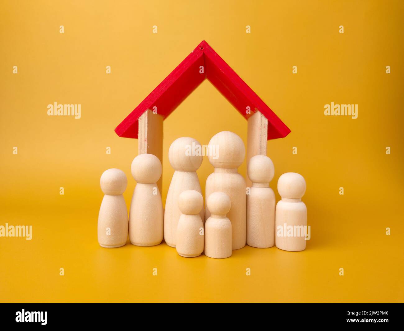 The wooden figures inside wooden house on yellow background with copy ...