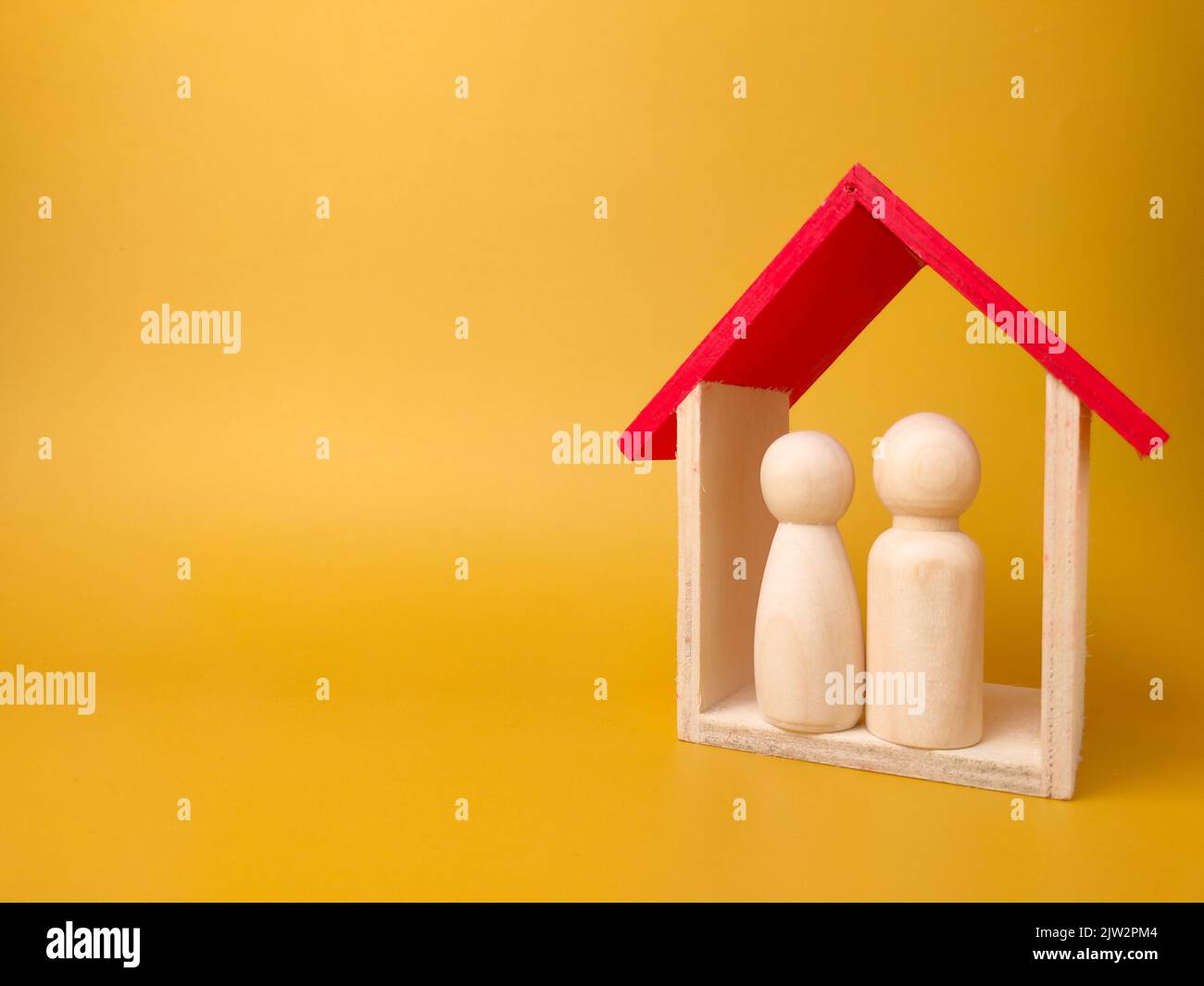 The two wooden figures inside wooden house on yellow background with ...