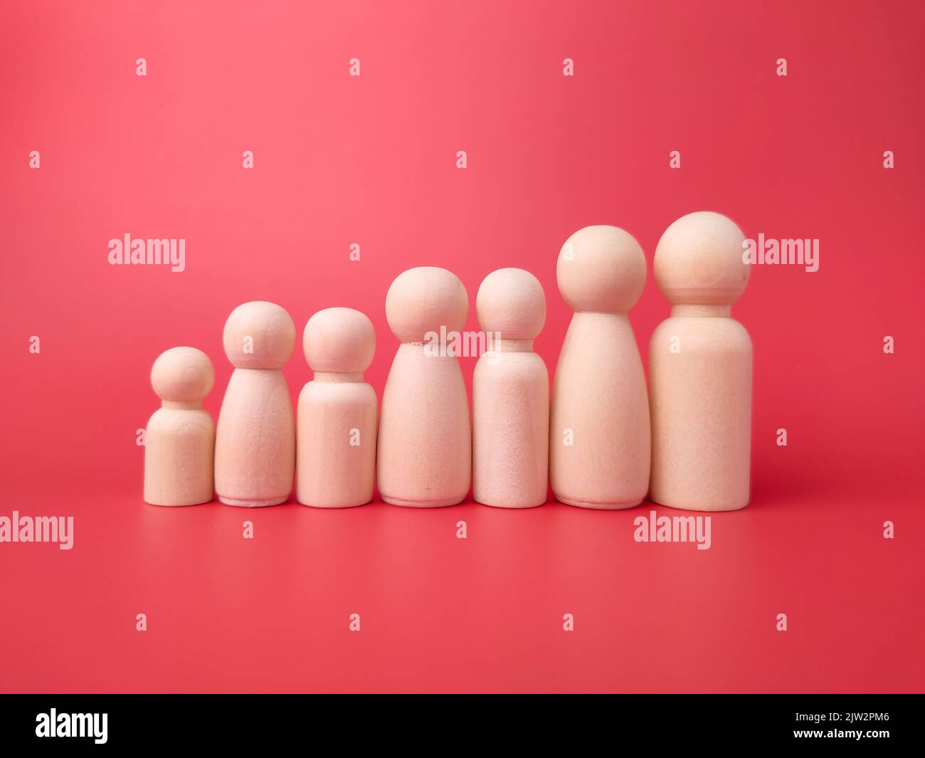 A family concept with plain wooden figures on red background with copy ...