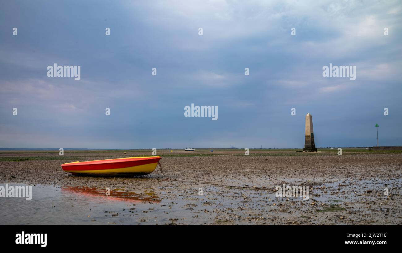 A rowing boat lies stranded at low tide next to The Crow Stone, the old ...