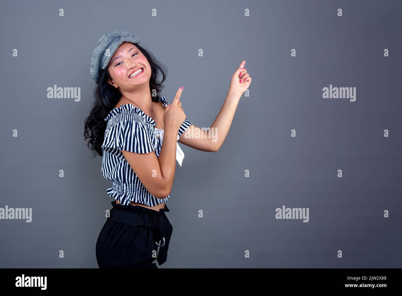 smiling young woman of Asian ethnicity pointing to her isolate in the ...
