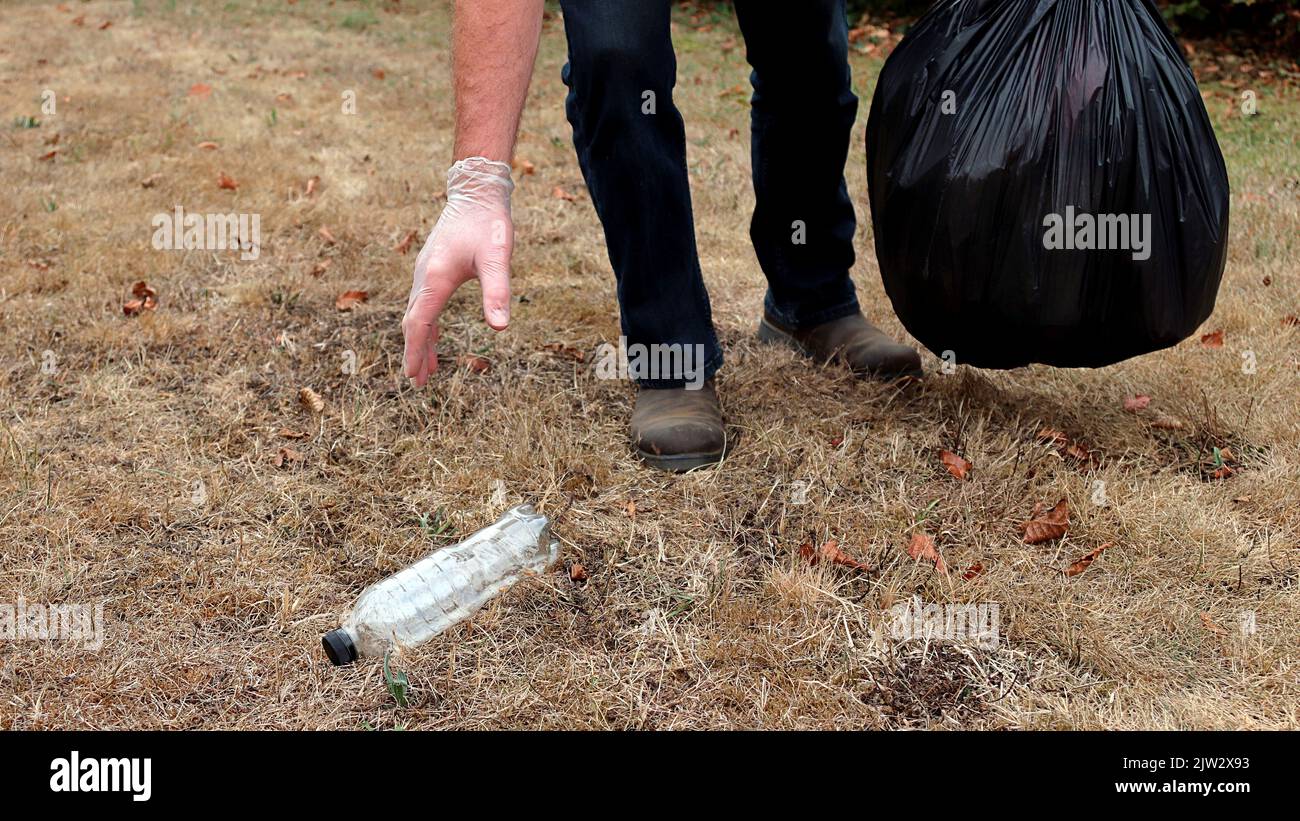 Hand and feet of person picking up litter in a park Stock Photo - Alamy