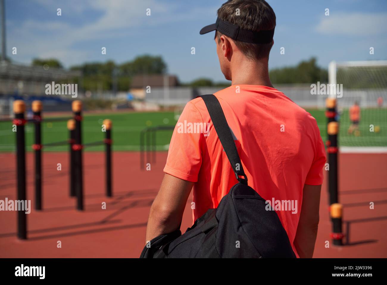 Back view of sportsman with bag standing at the open stadium. Sport ...