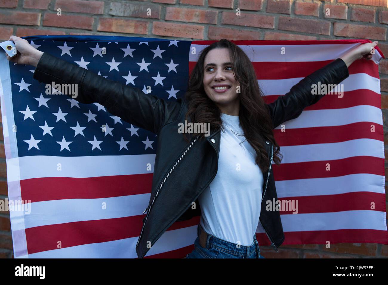Young caucasian smiling woman waving american flag in front of the ...