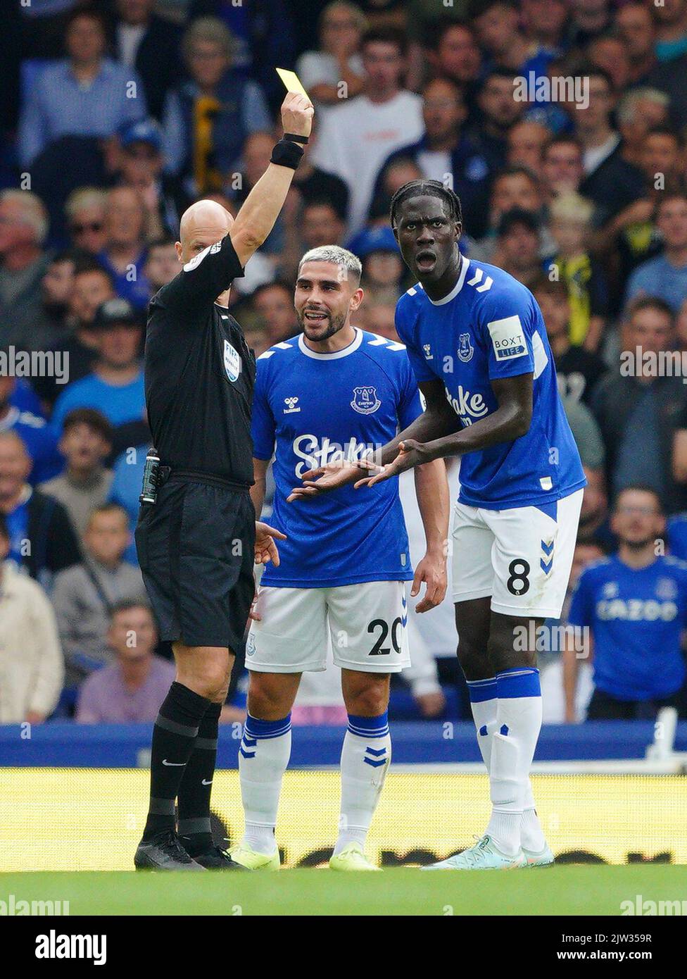Referee Anthony Taylor shows a yellow card to Everton's Amadou Onana ...