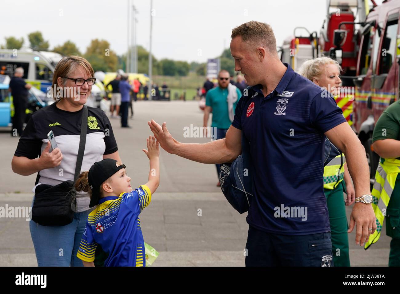 Jason Clark #14 of Warrington Wolves high fives a young fan as he ...