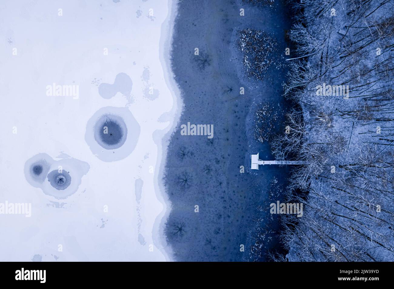 Pier, frozen lake and ice holes for fishing in winter, Poland. Aerial ...