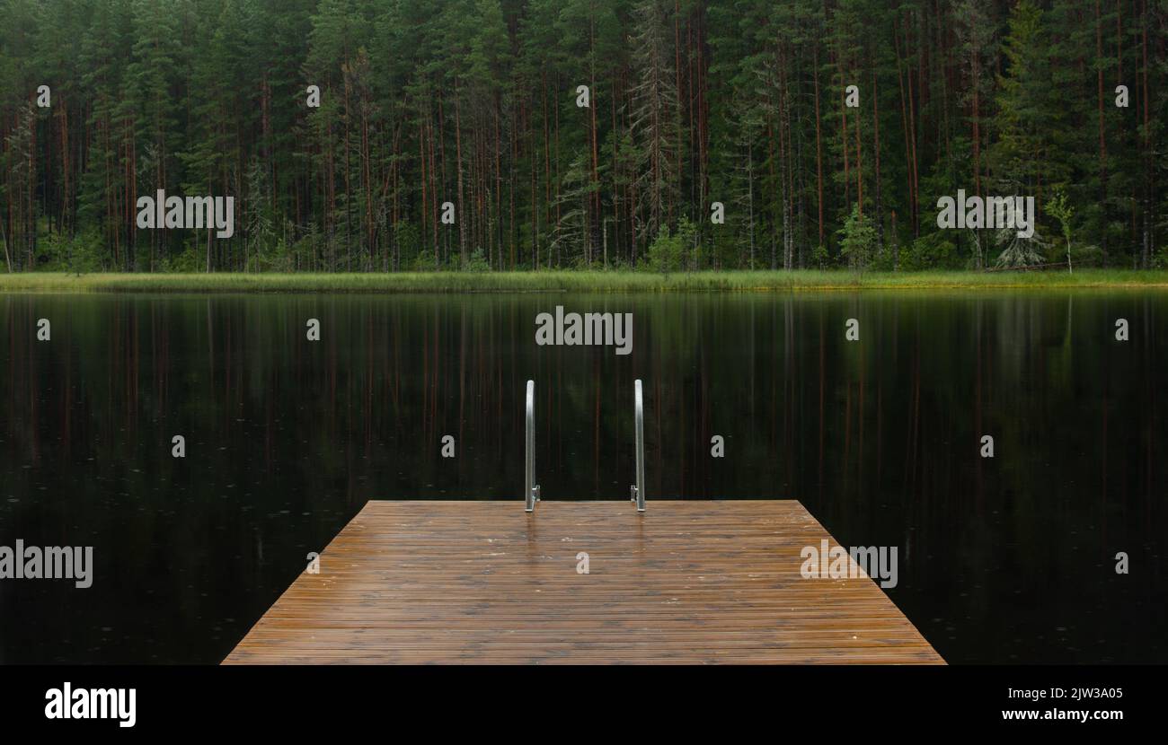 a peaceful swimming place at a forest lake with a deck and shallow ...