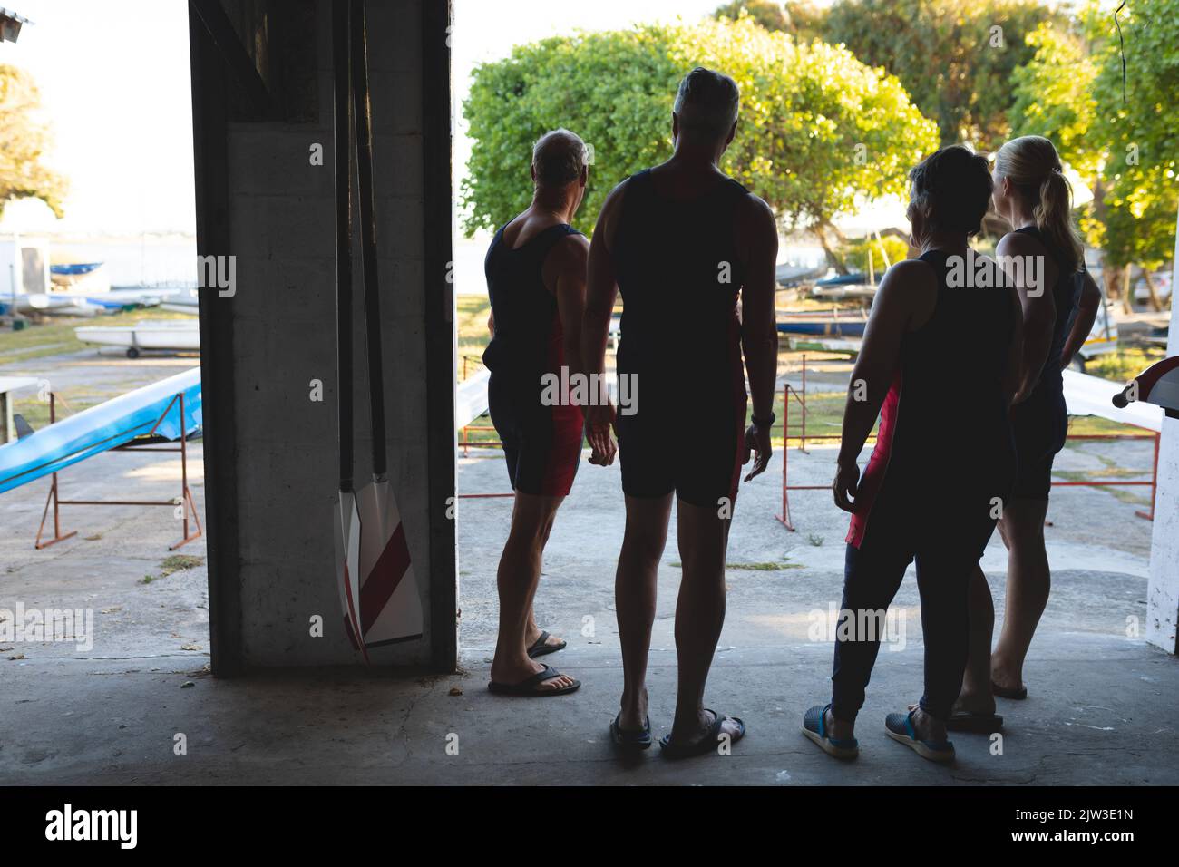 Rear view of senior caucasian rowing team standing together in the boat ...