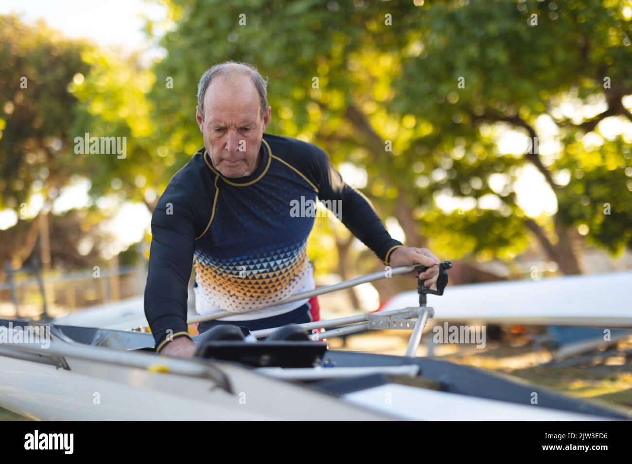 Senior caucasian male rower carrying boat together to the lake Stock ...