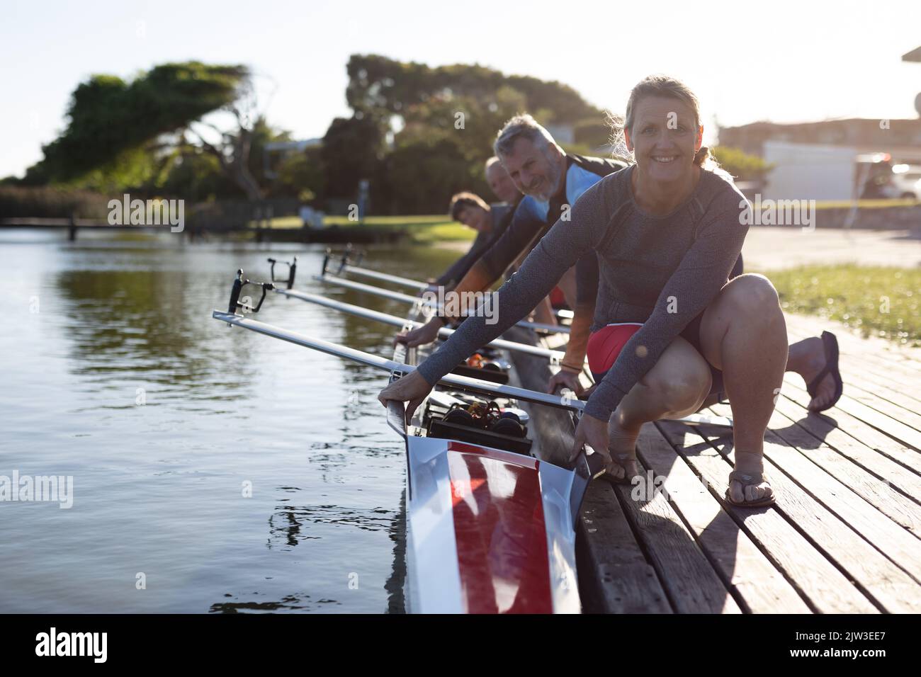 Portrait of senior caucasian rowing team holding the boat while sitting ...