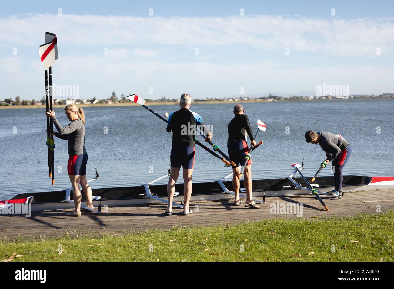 Senior caucasian rowing team attaching oars to the boat near the wooden ...