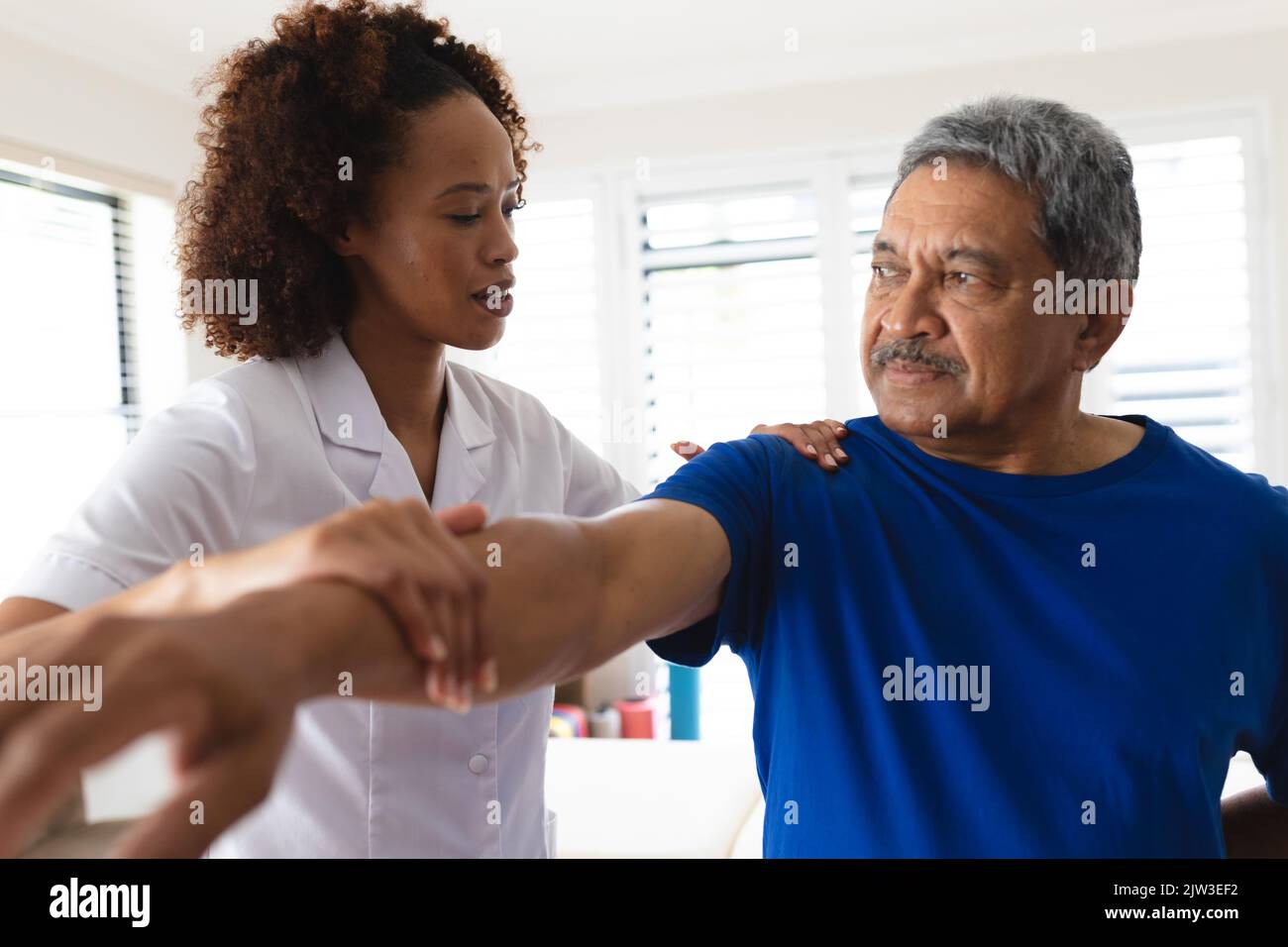 Mixed Race Female Physiotherapist Helping Senior Man Stretching His Arm