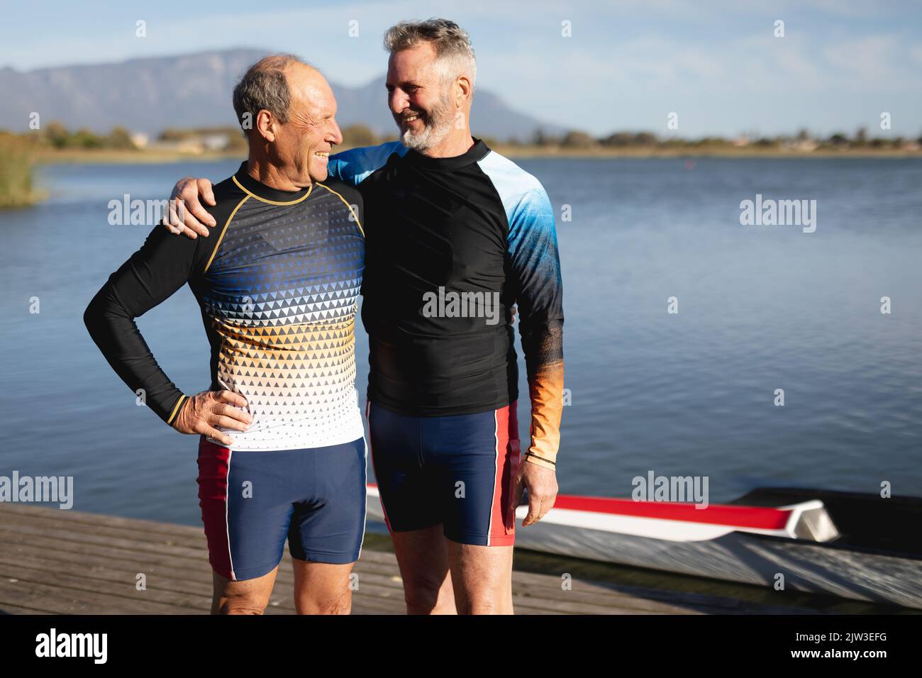 Two senior caucasian male rowers smiling looking at each other while ...