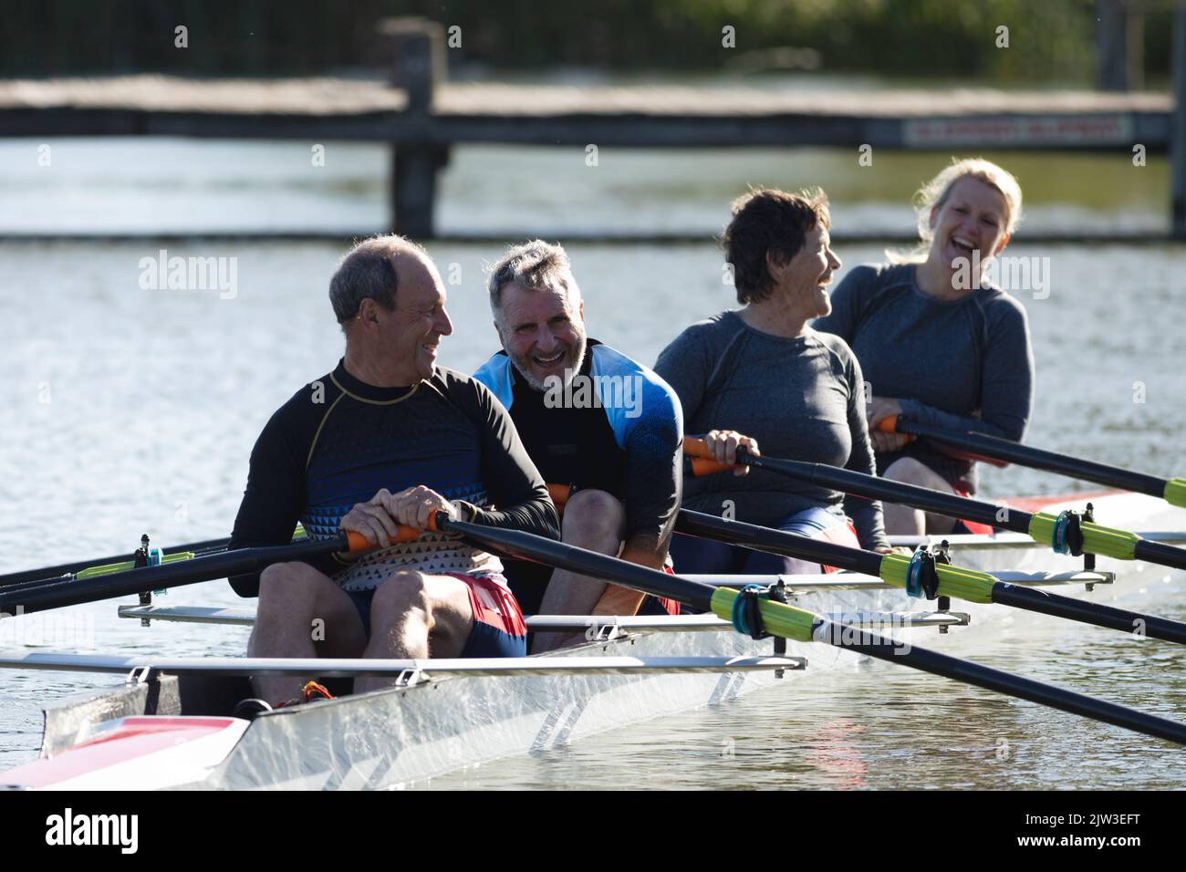 Senior caucasian rowing team smiling while rowing the boat on the lake ...