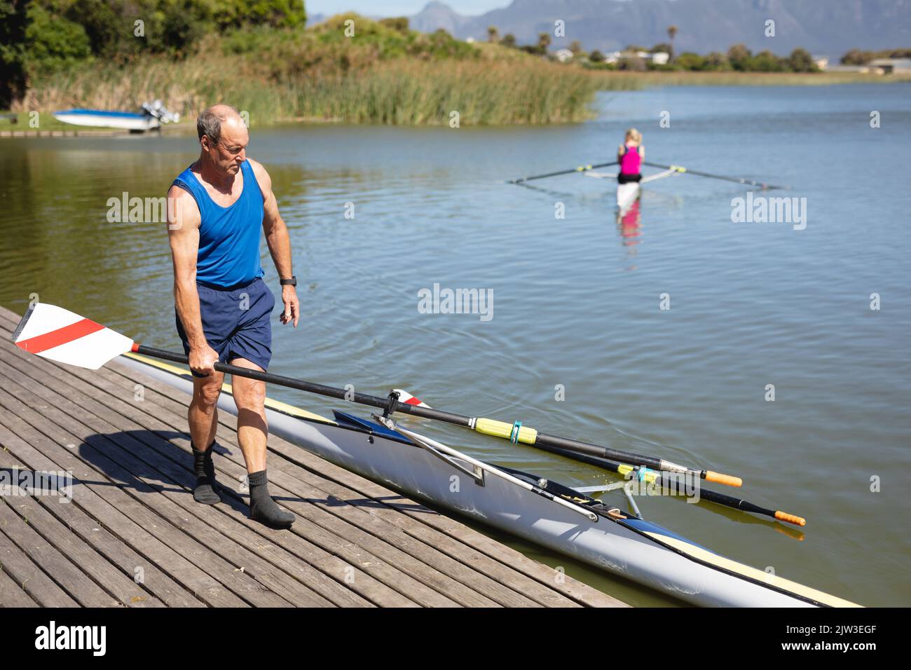 Senior caucasian male rower keeping boat oars in the boat while ...