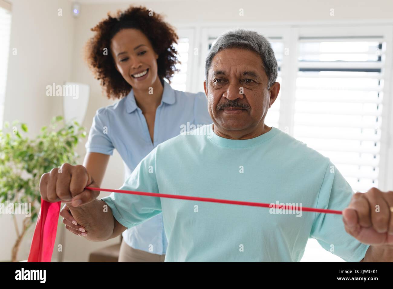 Mixed Race Female Physiotherapist Helping Senior Man Exercise Using