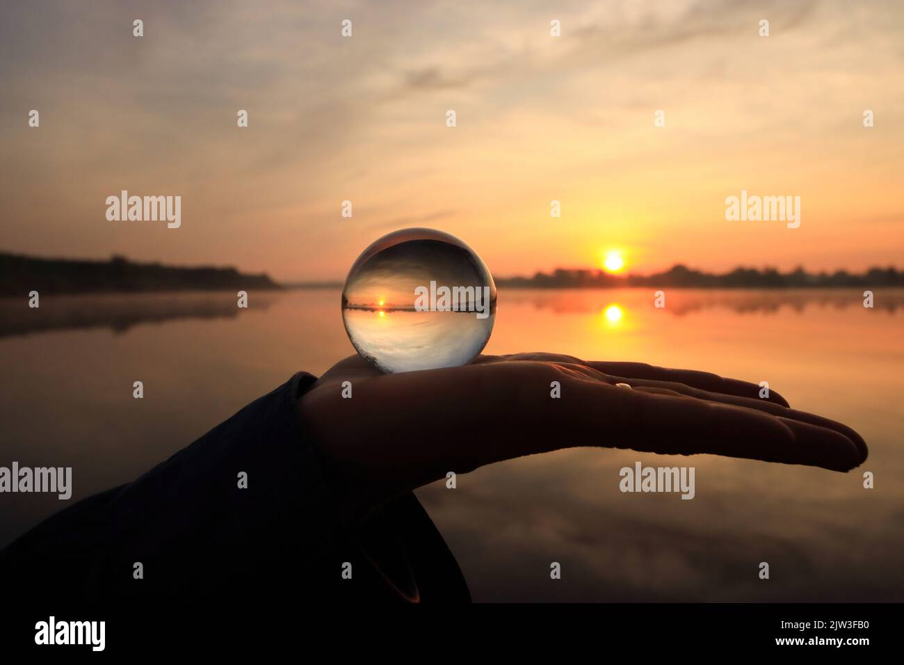 a beautiful sunset caught in a glass ball in hand Stock Photo - Alamy