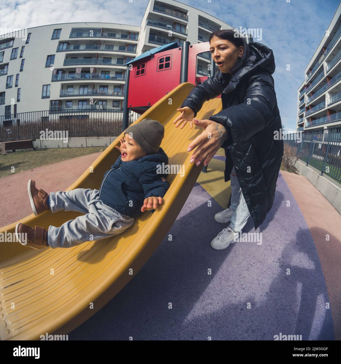 mom and her little child having fun at the playground on a winter day ...
