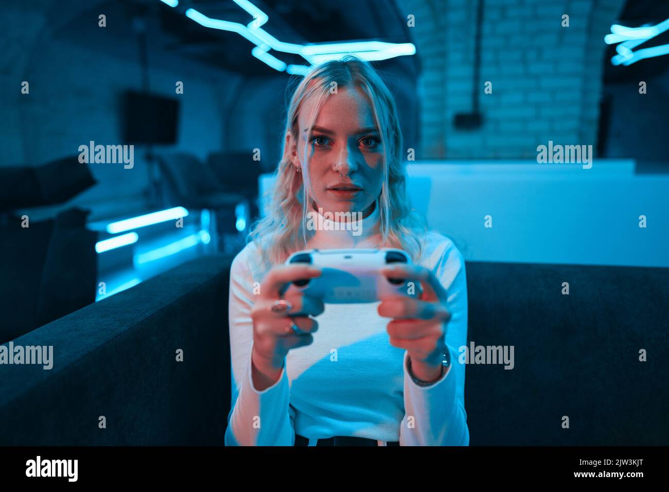 Portrait of a young woman playing a console in a neon room Stock Photo ...