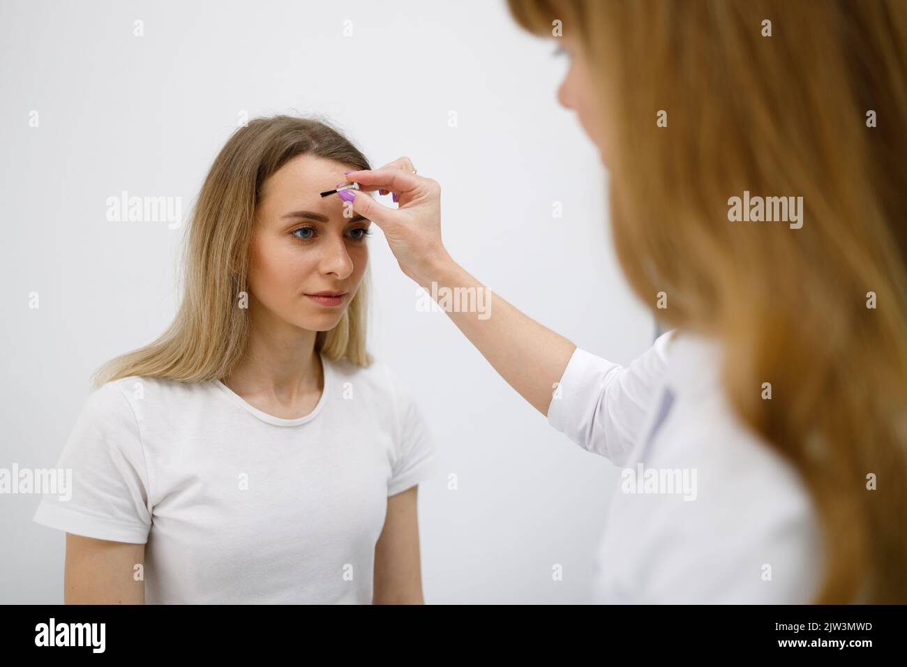 Neurologist doctor makes skin reflex test with special brush on a woman ...