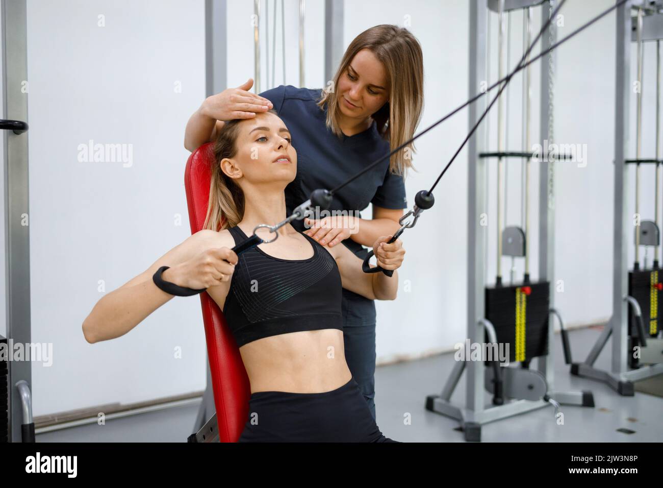 Young female patient at the gym doing physical exercises on wheight ...