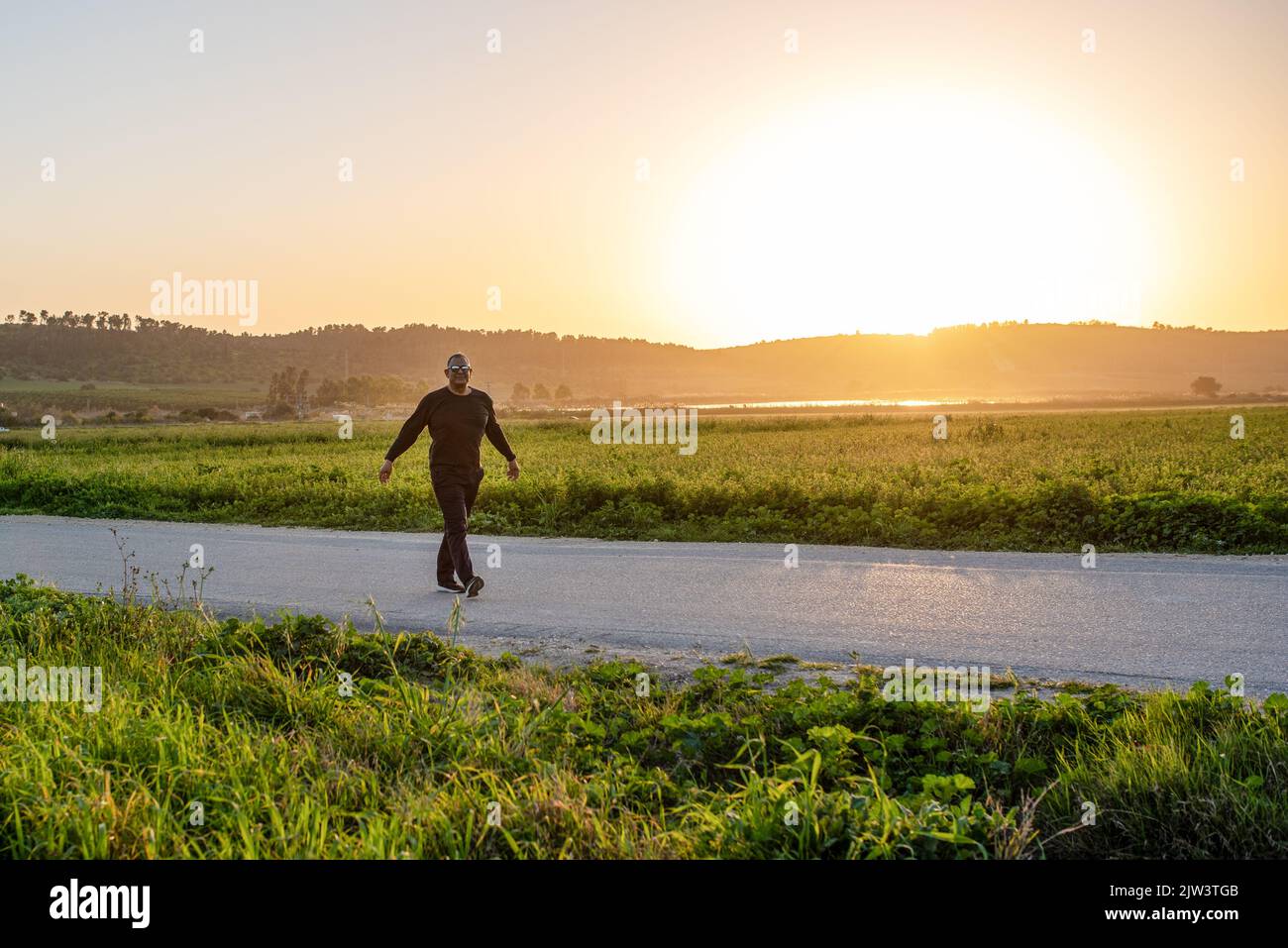 Senior athlete man walking on the sunset background Stock Photo - Alamy