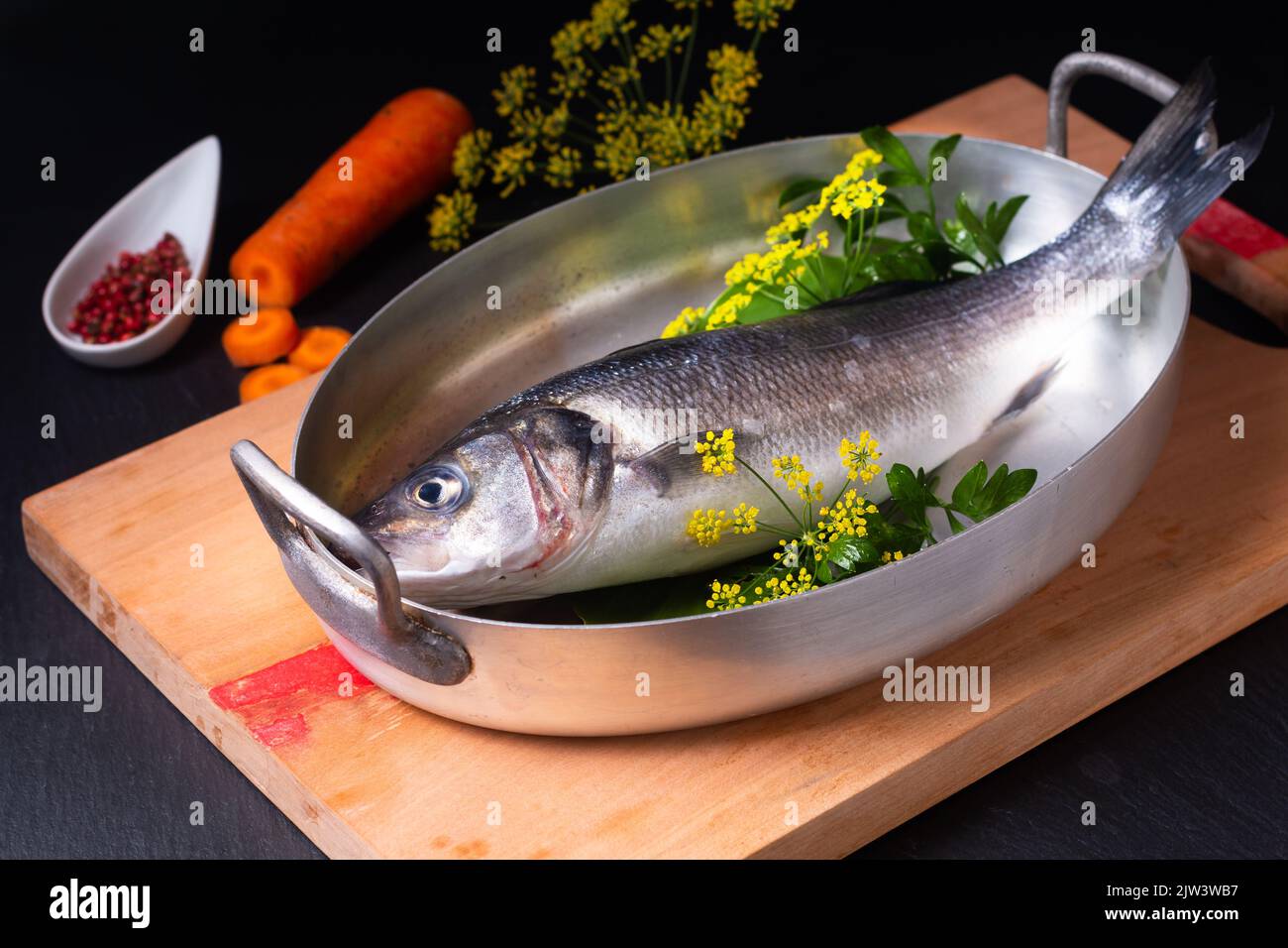 Food concept White Trout fish in tustic tray on wooden board on black ...