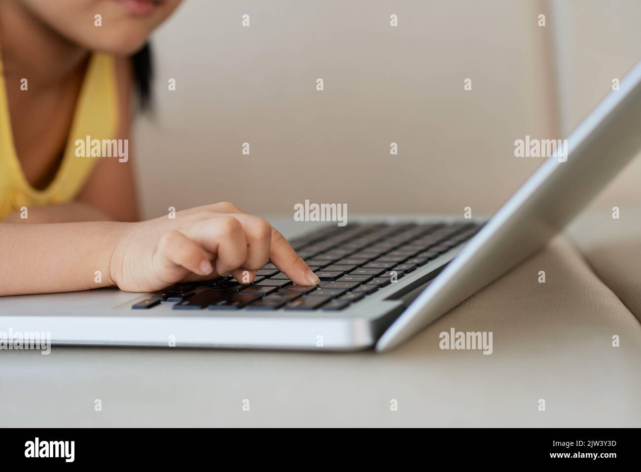 Smart little girl lying on laptop and working on computer Stock Photo ...