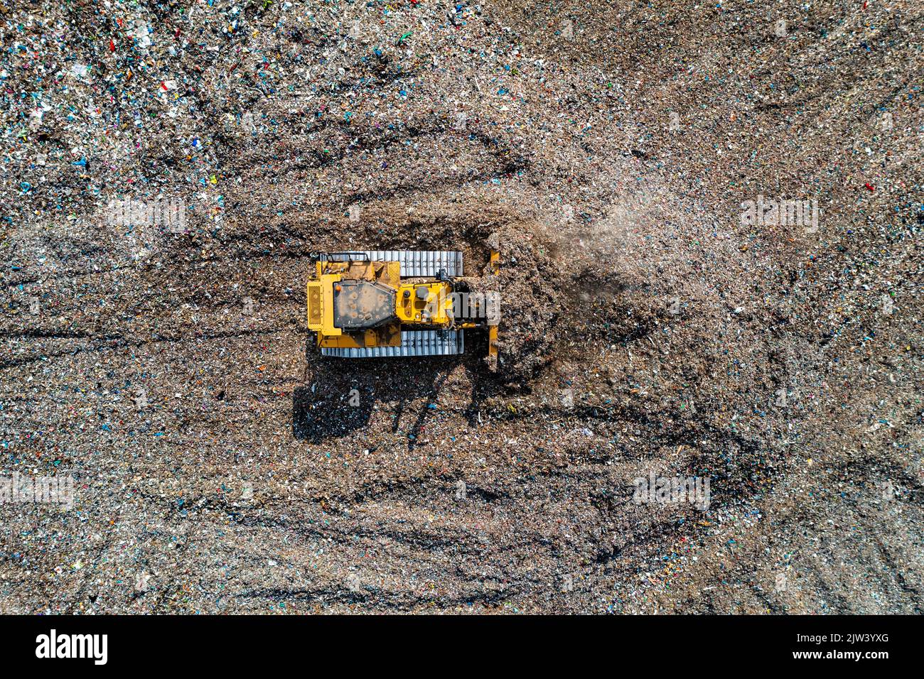 An aerial view of an industrial bulldozer moving household waste and ...
